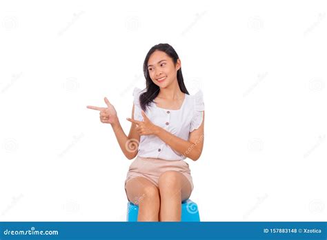 An Asian Girl In White Sitting On Blue Stool And Pointing To The Left