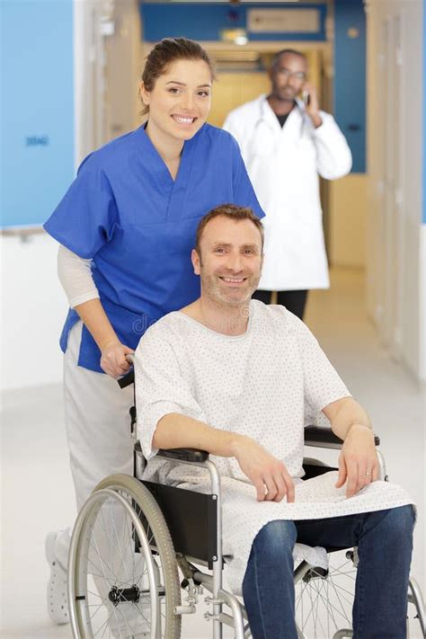 Happy Nurse Talking Care Happy Patient In Wheelchair Stock Photo