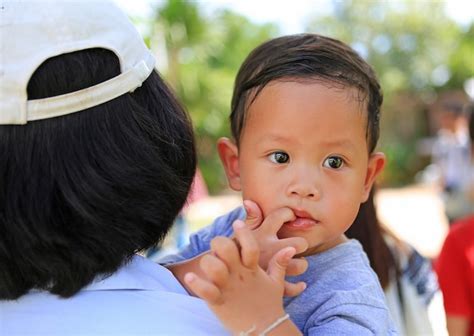 Bouchent La Mère Asiatique Transportant Son Fils Avec Sucer Le Doigt