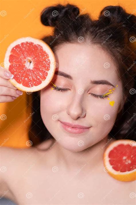 Jovencita Con Tajada De Pomelo Sobre Fondo Naranja Imagen De Archivo
