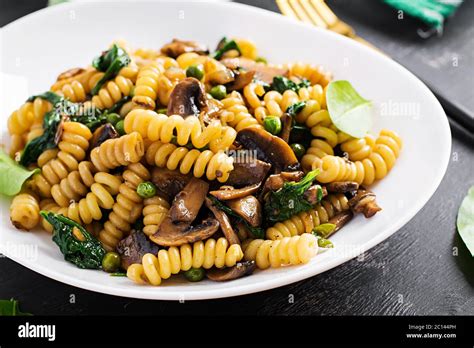 Fusilli Pasta With Spinach And Mushrooms On A White Plate Vegetarian