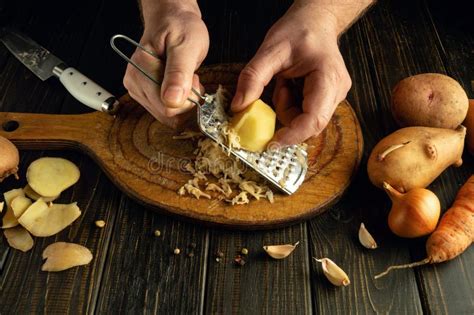 The Hands Of A Cook With A Grater Grate Raw Potatoes On The Kitchen