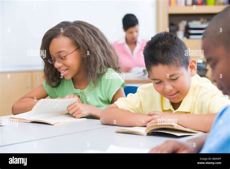 Students In Class Reading With Teacher In Background Selective Focus