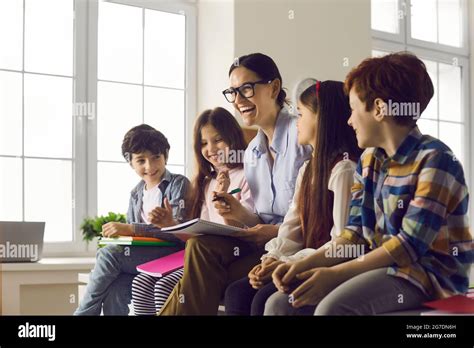Teacher And Pupils Laughing While Checking Task In Copy Book In