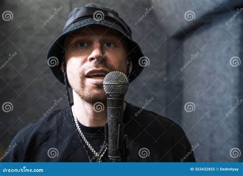Rapper Wearing Black T Shirt And Hat Looks Into Distance Stock