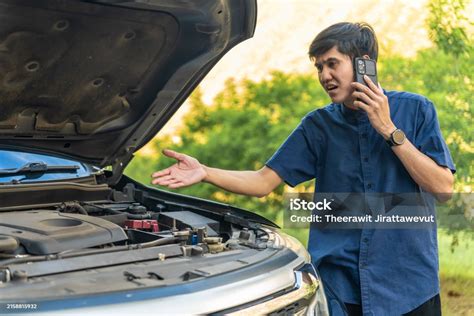 고속도로 길가에서 고장난 차에 문제가 있는 아시아 남성과 숲 속 도로에서 고장난 자동차의 열린 후드 앞에서 휴대전화 통화 차고를 사용하고 있습니다 자동차 고장 개념 25