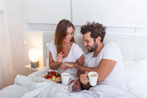 Young Handsome Man Feeding Attractive Young Woman In Bed In The Morning