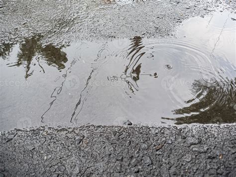 The Afternoon Sky Was Reflected In A Puddle Of Water On The Sidewalk