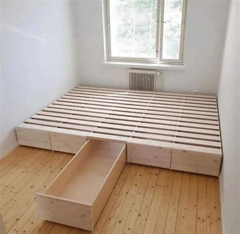 A Bed Frame With Drawers Underneath It In A Room Next To A Window And
