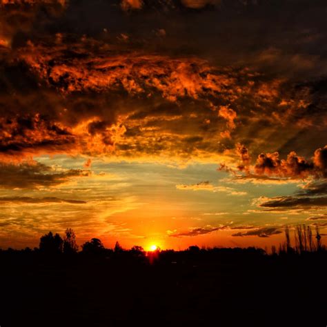 Download Majestic Orange Sunset Behind Dusky Clouds Wallpaper