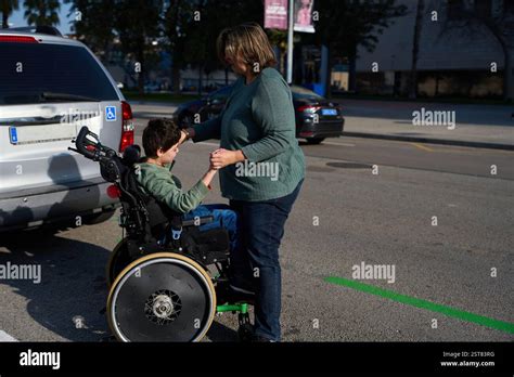 Mother Helping Son With Disability Getting Out Of Car In Wheelchair