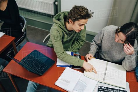 High Angle View Male Student Assisting Female Classmate At Desk In