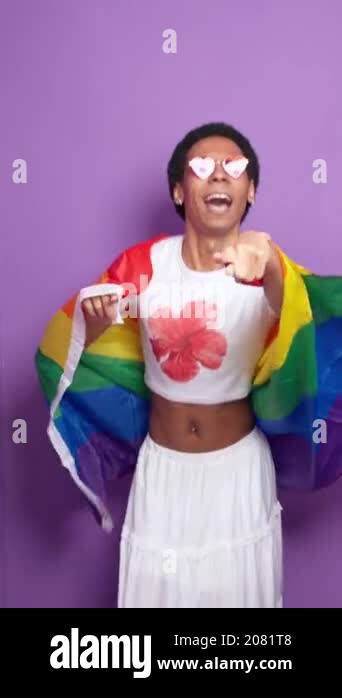Joyful Non Binary Activist Dancing With Rainbow Flag Against Purple
