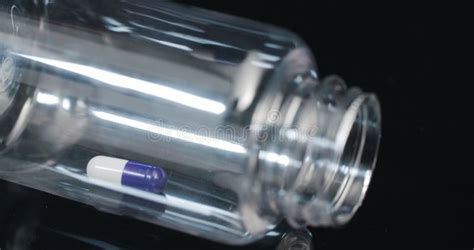Single Medical Pill In Small Bottle Rotating On Black Background Stock