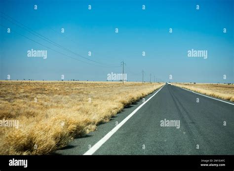 Long Straight Road Near Corfield In Rural Australia With Dry Grasss And Clear Blue Sky Stock