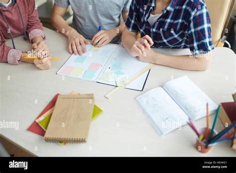 Desk With Notebooks And Students Of Design Faculty Carrying Out