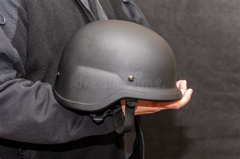 A Man Wearing Body Armour Holds A Tactical Military Helmet In His Hand
