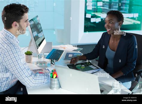 Executives interacting with each other at desk in office Stock Photo - Alamy