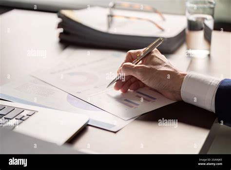 Elderly Businessman Analyzing Financial Reports And Charts While Taking