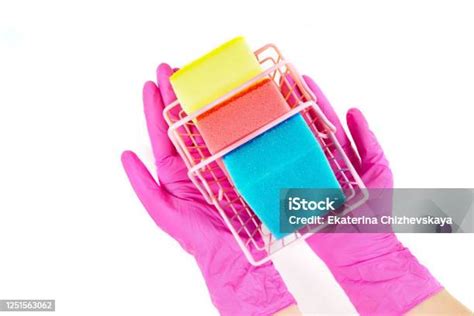 분홍색 일회용 장갑을 착용한 여성의 손에는 여러 가지 색의 접시 세척 스폰지로 가득 찬 작은 쇼핑 바구니를 들고 있습니다 맨 위 보기 흰색에 격리 가사 집안일에 대한 스톡
