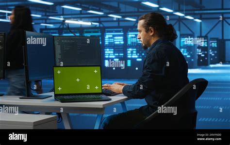 Engineer Upgrading Equipment In Data Center Using Green Screen Laptop Specialist At Pc Desk In