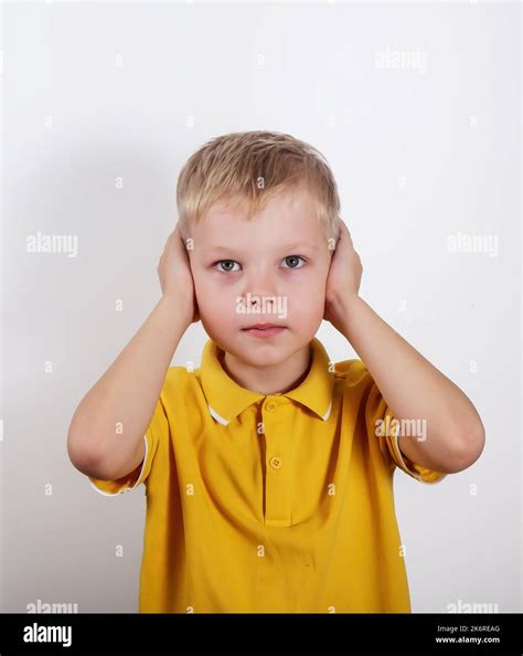 A Boy In A Yellow T Shirt Shows Covering His Ears With Both Hands