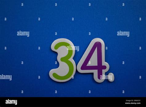 The Number 34 Placed On A Blue Background Photographed From Above Colored Green And Purple
