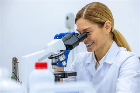 Scientist Looking Under Microscope Doing Analysis Of Test Sample