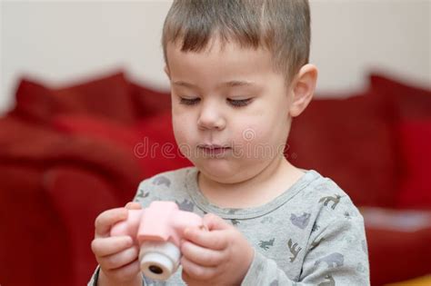 Cute Boy Playing With A Toy Camera While Watching Tv At Home By The