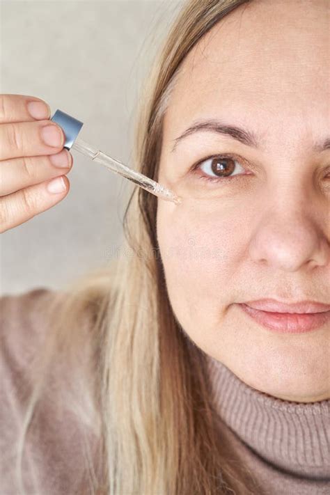Caucasian Mature Female Applying Face Serum With Dropper For Skincare