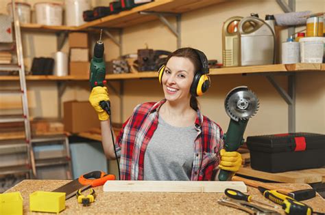 격자 무늬 셔츠 회색 티셔츠에에서 젊은 갈색 머리 여자 소음 절연 헤드폰 노란색 장갑 파워 본 다른 도구로 나무 테이블 장소에