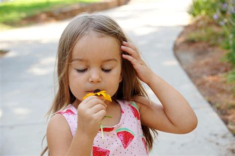 Premium Photo Cute Girl With Eyes Closed Smelling Coneflower At Park