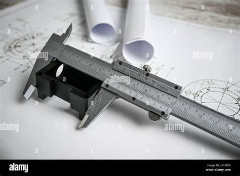 Caliper Measuring A Plastic Component On Top Of Technical Drawing
