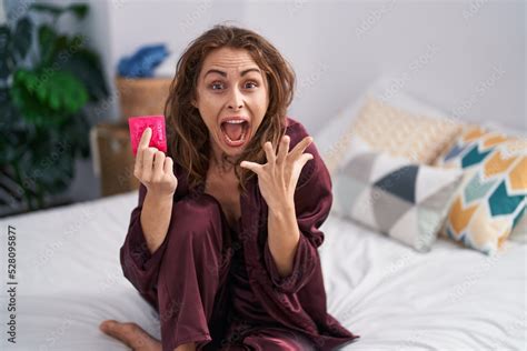 Beautiful Brunette Woman Holding Condom At The Bedroom Celebrating