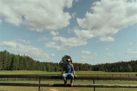 Man In Blue Denim Vest And Blue Denim Shorts Standing On Green Grass
