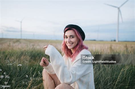하얀 풍차와 필드에 앉아 모자에 분홍색 머리를 가진 아름 다운 행복 한 여자 분홍 머리에 대한 스톡 사진 및 기타 이미지 분홍 머리 한 명의 여자만 여자만 Istock