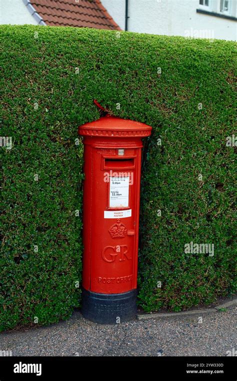 A Red British Post Box Stands Embedded In A Neatly Trimmed Green Hedge