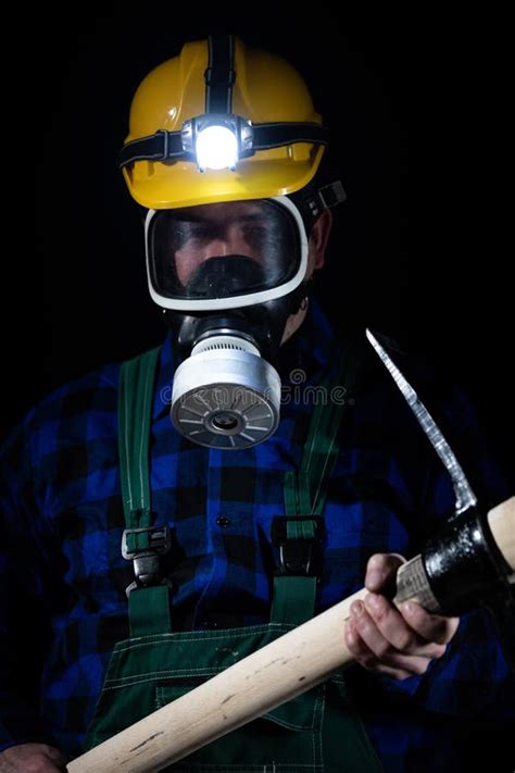 A Miner Wearing A Helmet With A Flashlight And A Dust Mask Holds A Bucket Full Of Black Coal In