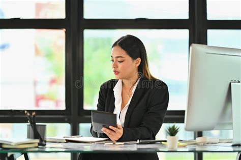 Focused Female Analyst Looking At Laptop Using Calculator Checking Marketing Research Results