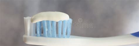 Toothbrush And Toothpaste Close Up On Gray Blurred Background Stock