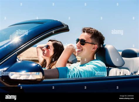 Portrait Of Attractive Young Man Driving With Girlfriend In Blue