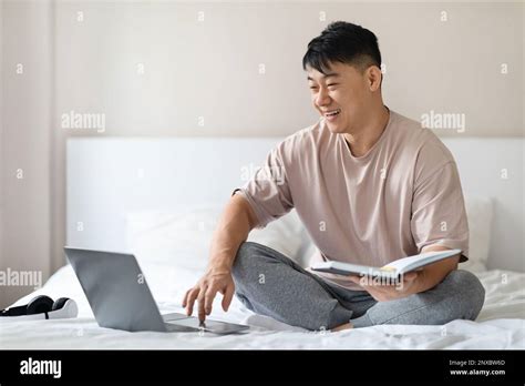 Chinese Man Checking Notepad Using Brand New Laptop In Bed Stock Photo Alamy