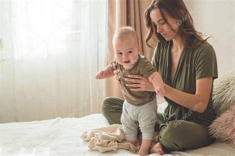 Retrato Casero De Un Niño Con Madre En La Cama Mamá Sosteniendo Y
