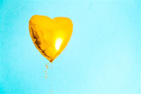 복사 공간이 있는 파란색 배경에 리본이 있는 하나의 큰 노란색 하트 모양의 풍선 사랑의 상징입니다 아름 다운 생일 파티 선물입니다 부동 개체 헬륨 가스에 의해 팽창식 엽서