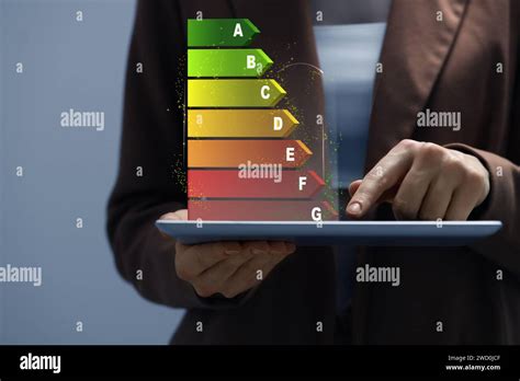 Energy Efficiency Rating Coming Out Of Tablet Man Using Device On Grey