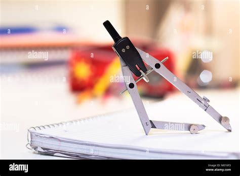 A School Metal Drawing Drafting Compass On A Notebook With Spiral