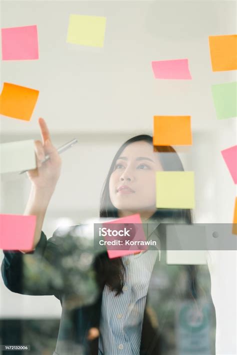 브레인 스토밍의 개념은 사업가가 유리 벽에 놓는 포스트잇 메모를 사용하여 아이디어를 공유 할 때 예시됩니다 리더십에 대한 스톡 사진 및 기타 이미지 Istock