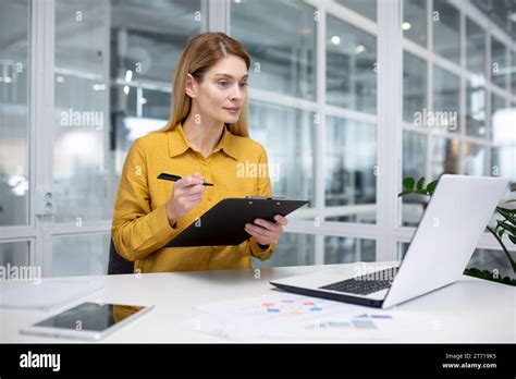 An Attractive Blonde Woman Works In A Modern Office Sits At A Desk In