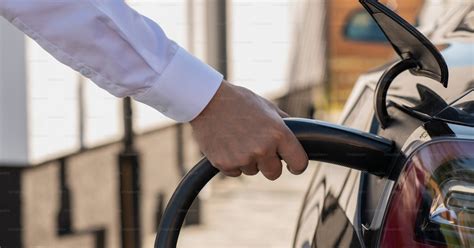 꽂힌 충전기를 들고 역에서 새 전기 자동차를 충전하는 젊은 남자의 손 사진 Unsplash의 자동차 이미지
