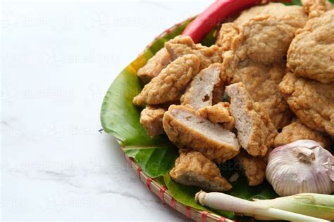 Image Of Deep Fried Cha Lua Slices Served On A Banana Leaf In A Woven